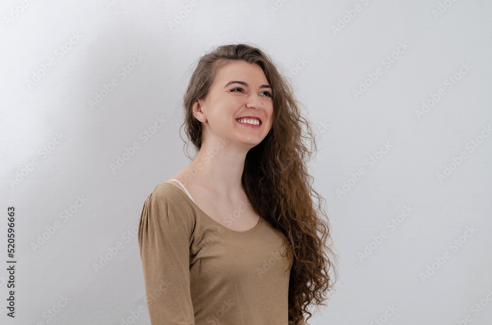 Cute girl with long dark curly hair. Posing, smiling. Side view. Gray ...