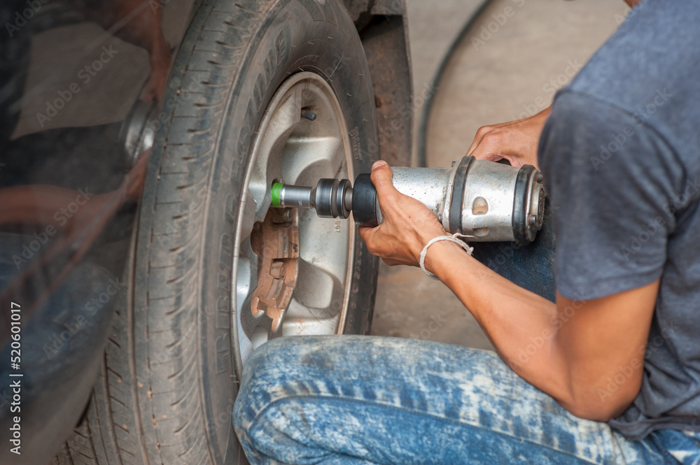 The mechanic uses a tool to remove the nuts from the wheels of a car ...