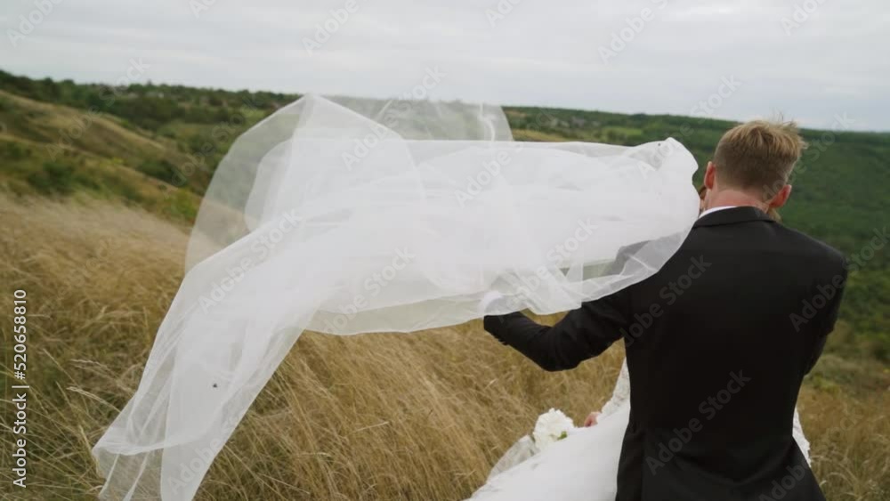 A white veil blowing in the wind. Couple standing in the canyon. Slow ...