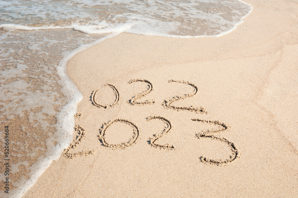 Inscription 2022 and 2023 numbers written on sand. New Year 2023 ...