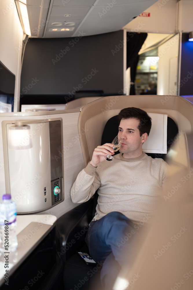 Rich man drinking champagne while flying aboard a first class flight ...
