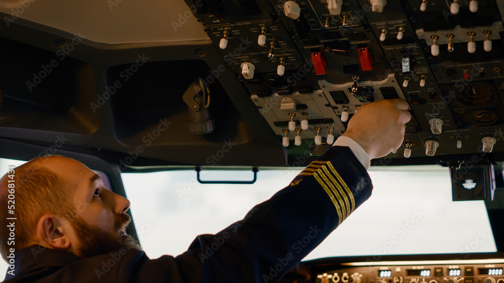 Airplane captain starting engine with power buttons on dashboard to fly ...