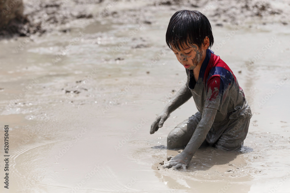 cute happy asian little boy enjoying to play in the mud at playground ...