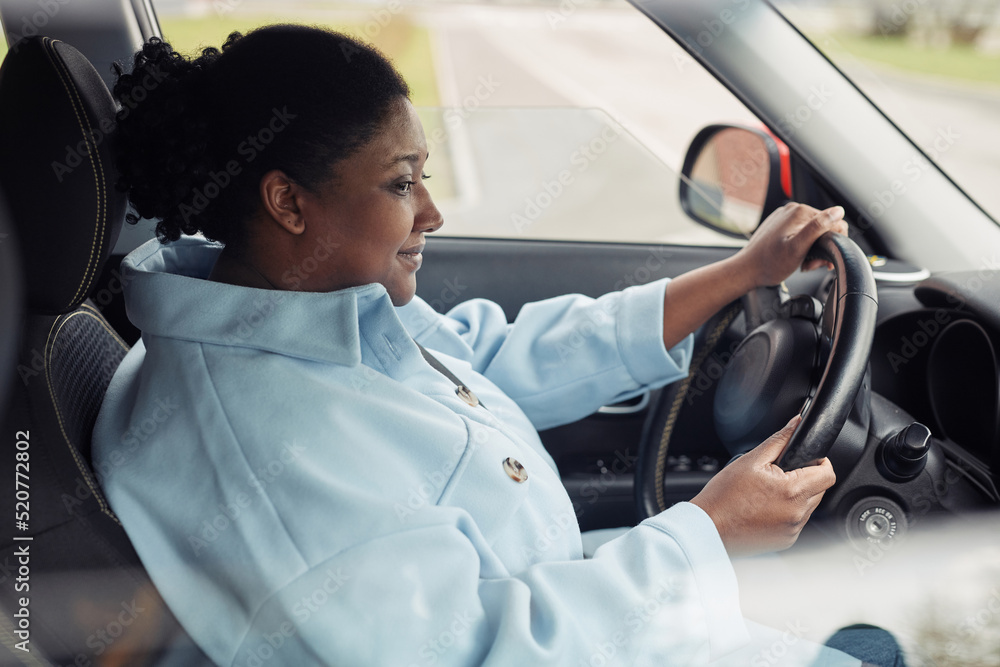 Side view portrait of young black woman driving car behind window, copy ...