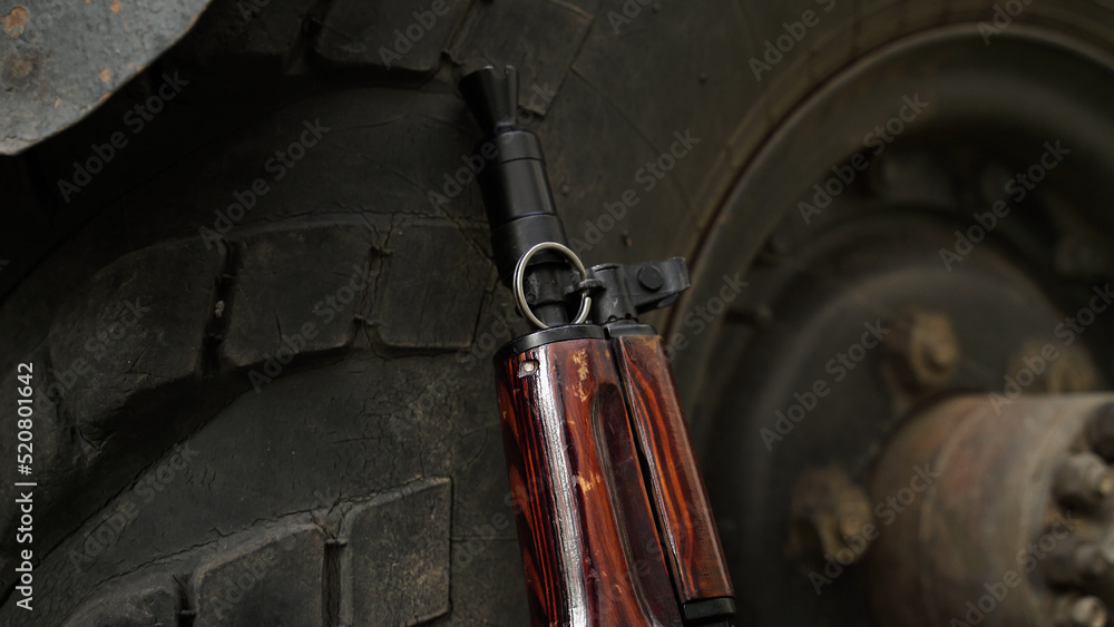 a Kalashnikov assault rifle lies next to the wheel of an armored ...