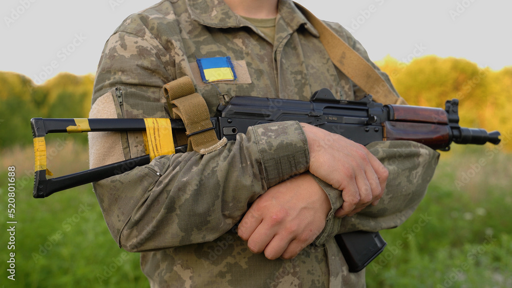 a Ukrainian soldier in camouflage holds a machine gun in a combat ...
