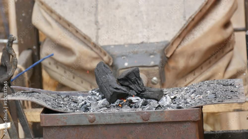 Medieval method of forging iron, the blacksmith forges an iron nail ...