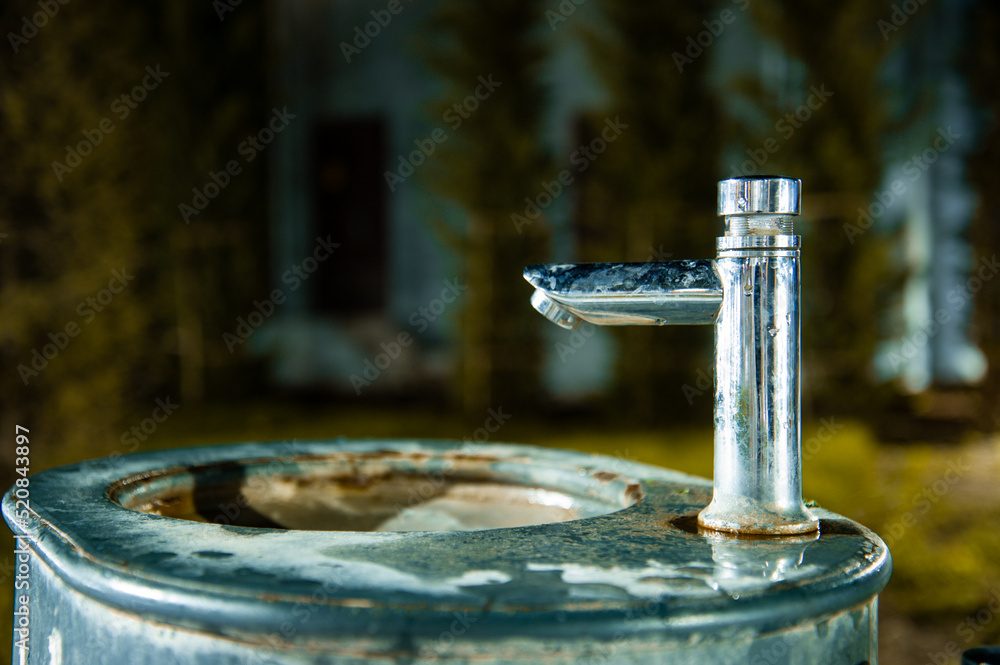 Silver fountain in a public park. There are water spots on the fountain ...