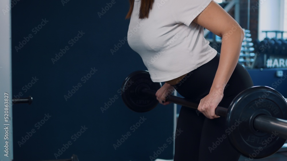 Athletic woman pumps muscles using a barbell with a weight. Classes in ...