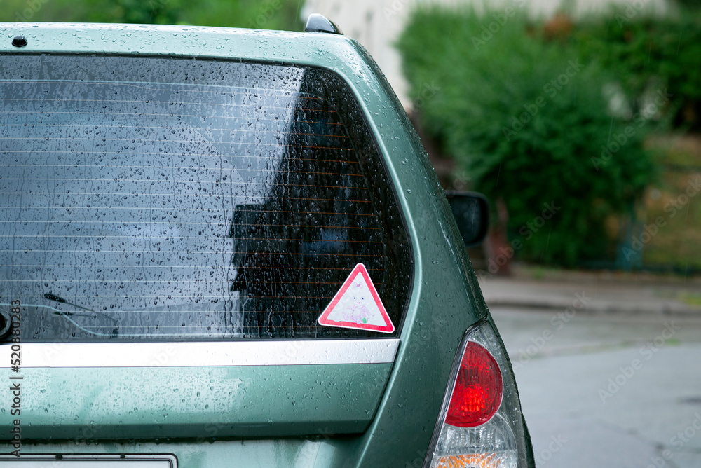 Back window of a green car parked on the street in rainy day, rear view ...