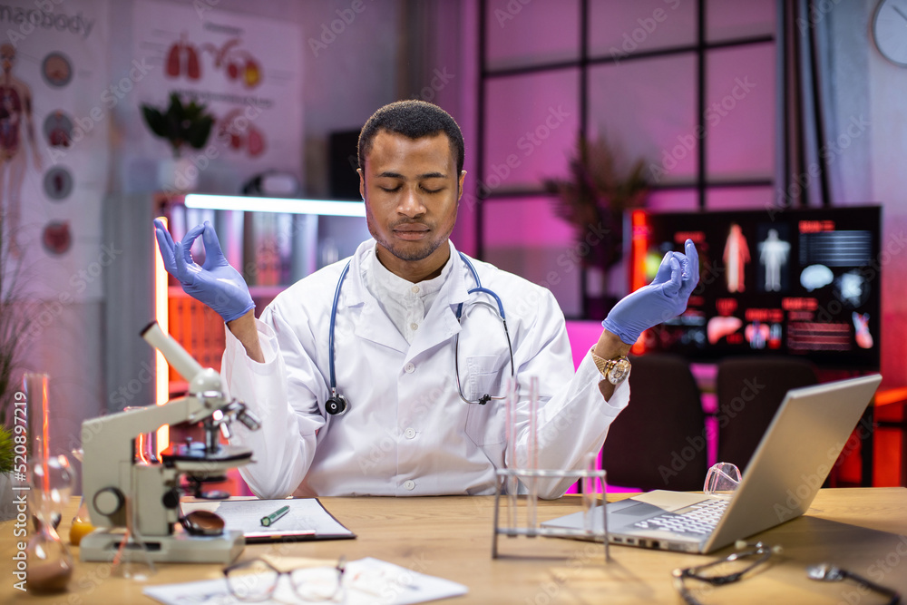 Yong african american male scientist relaxing practicing yoga wearing ...