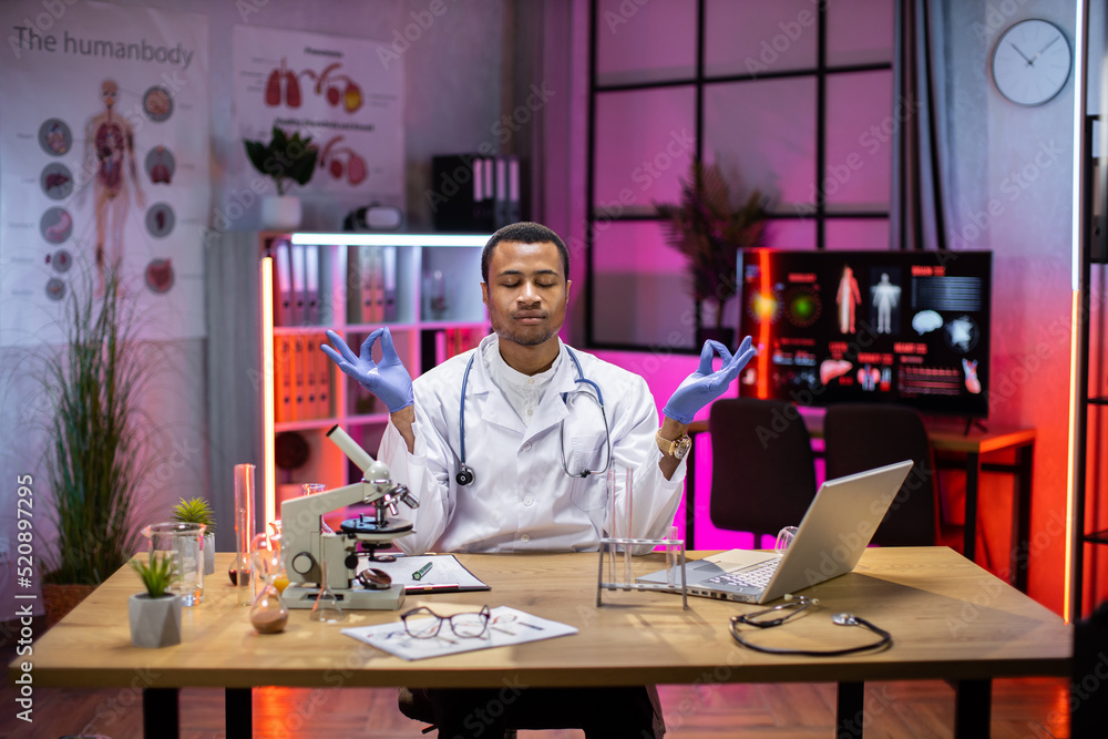 Yong african american male scientist relaxing practicing yoga wearing ...