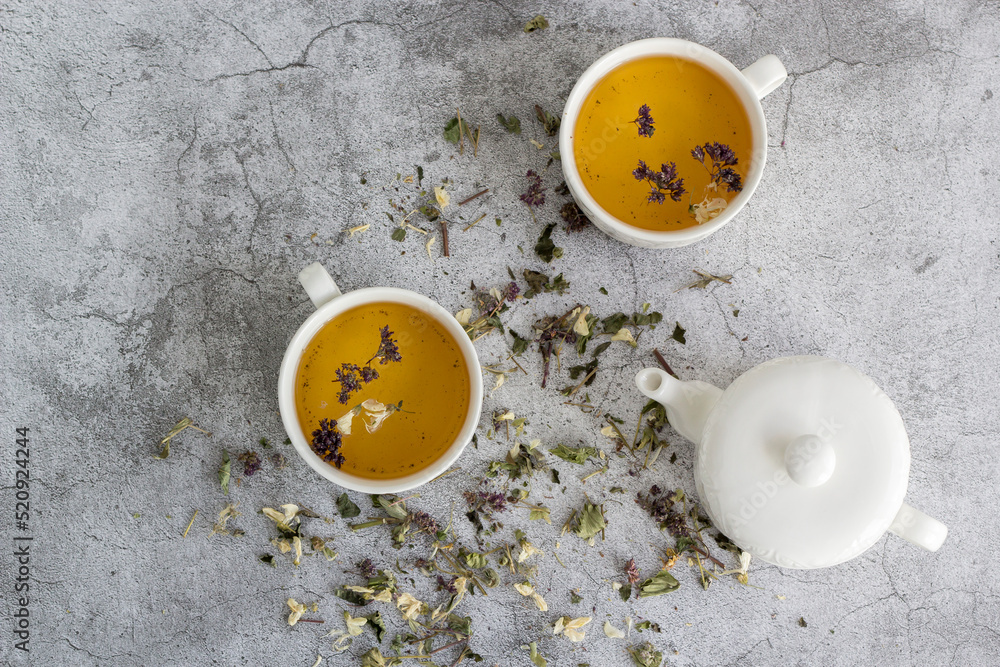 Herbal tea with two white tea cups and teapot, with green tea leaves ...