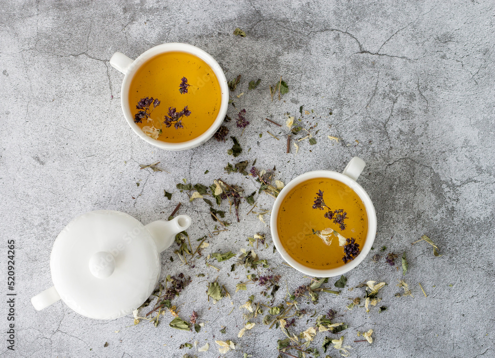 Herbal tea with two white tea cups and teapot, with green tea leaves ...