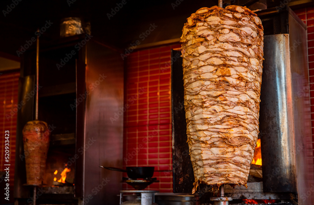 Arab Shawarma of meat chicken preparation placed on spit grilled with ...