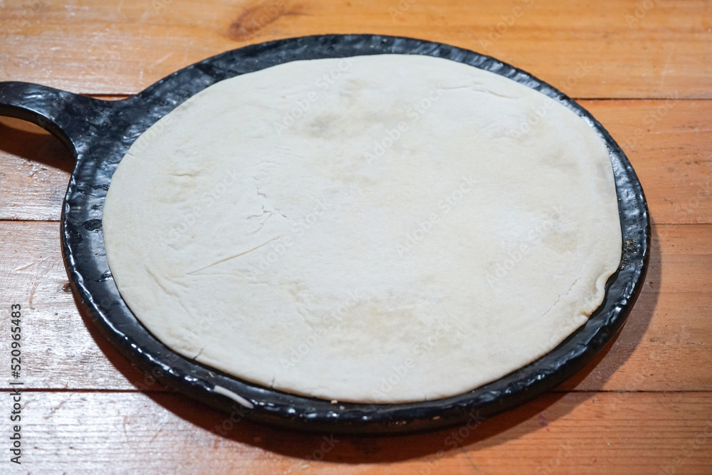 After kneading the pizza dough, it is placed in a pizza baking pan to ...