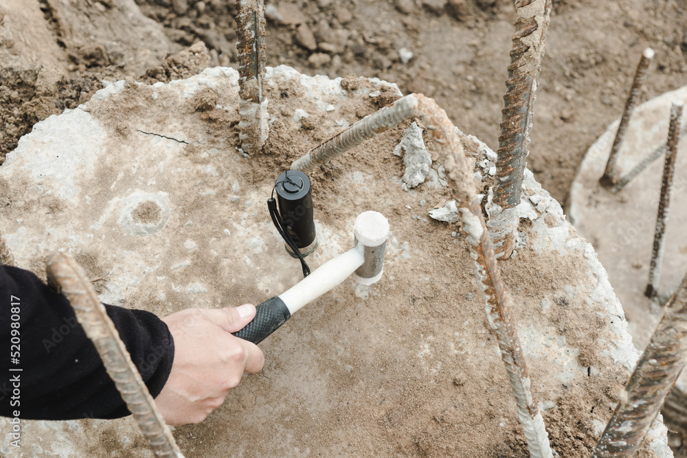 Seismic test on concrete pile. Engineer using the PIT Hand-Held Hammer ...