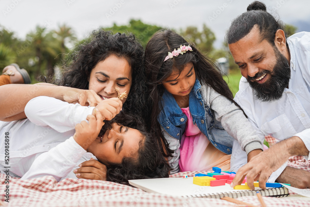 Happy indian family having fun playing with children outdoor at city ...