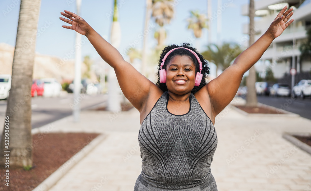 Happy curvy african woman celebrating during workout routine outdoor ...