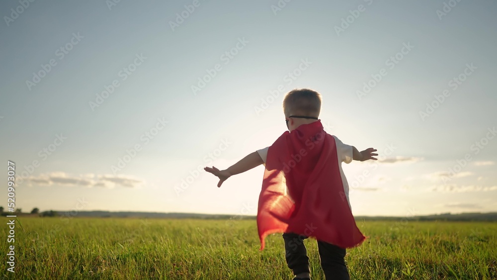 superhero. little boy running across the field in a superhero costume ...