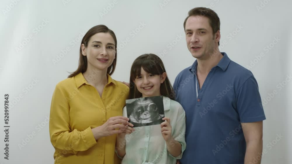 Young parents and their daughters look at ultrasound film approaching ...