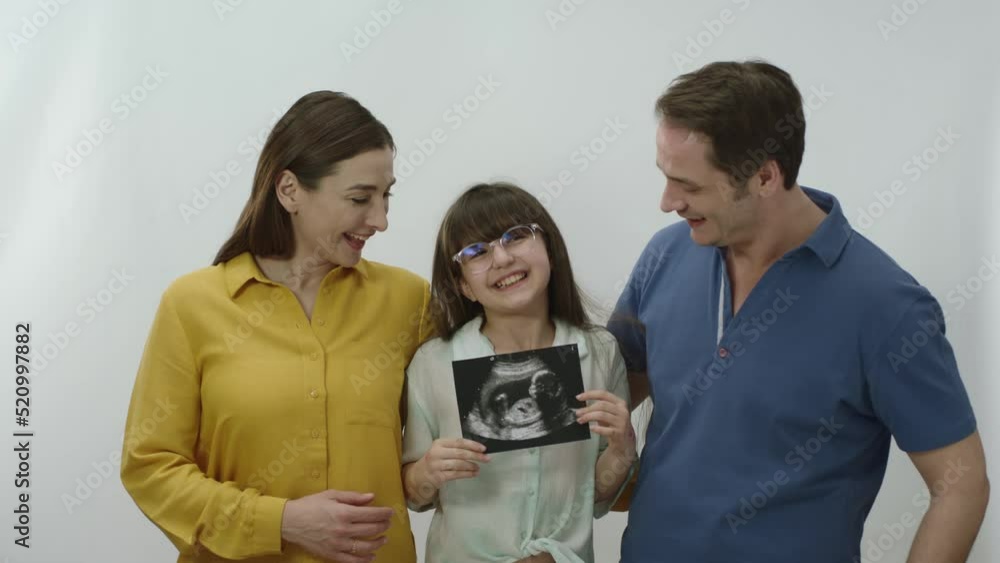 Young parents and their daughters look at ultrasound film approaching ...