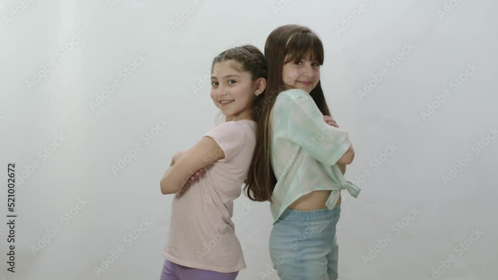 Two girls lean against each other in isolation. Energetic little girls ...
