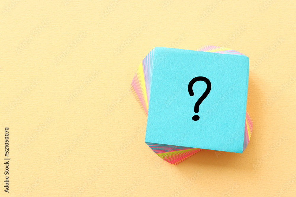 Top view image of sticky note and question mark over textured paper ...