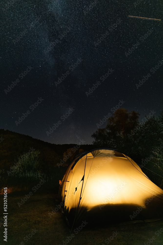 Bright illuminated tourist tents glowing on camping site in dark ...