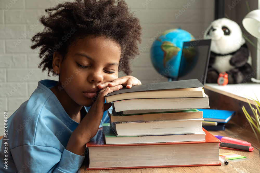 Tired African-American girl with closed eyes doing homework at home ...