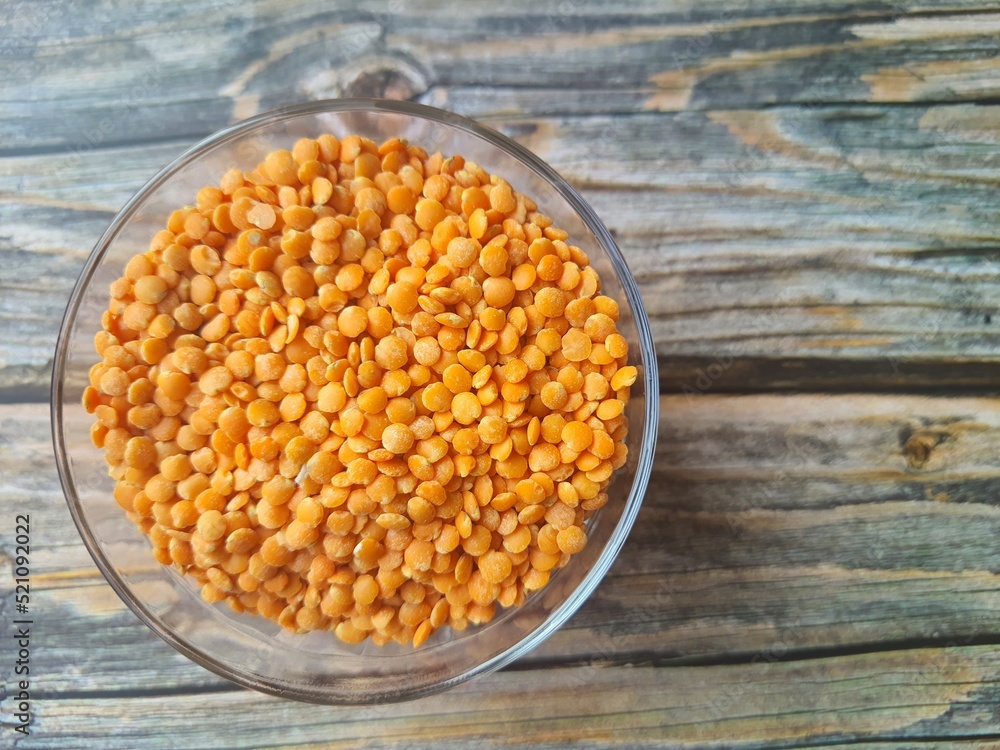 Orange lentils in a bowl on wooden table, top view. Culinary lens ...