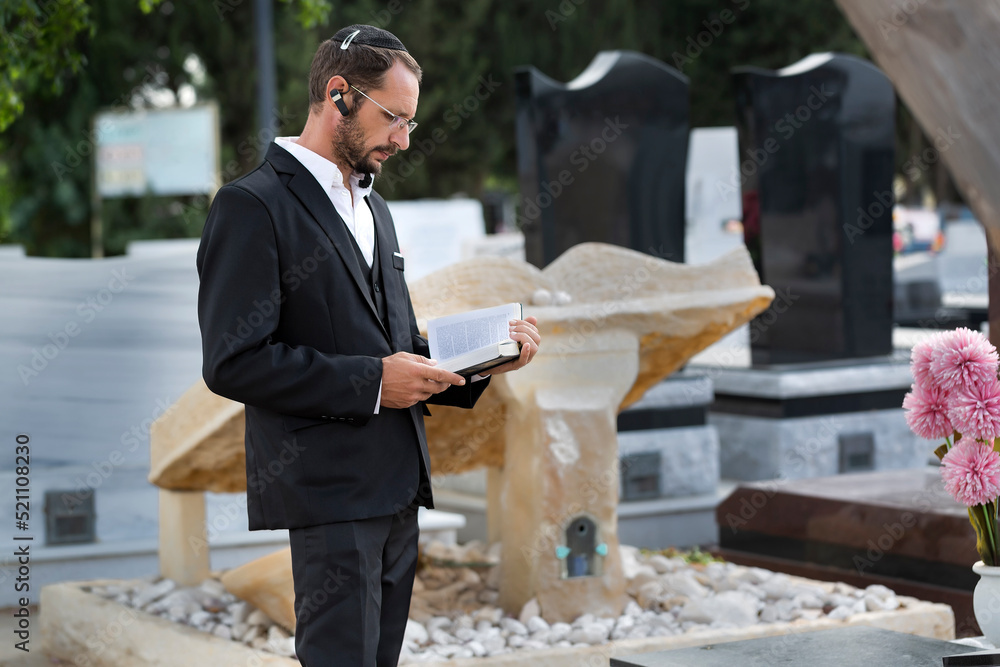Bearded Jewish man wearing black kippah (skullcap) reading a Hebrew ...