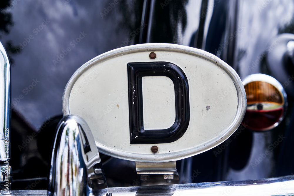 Oval badge made of white sheet metal with black letter D to mark the ...