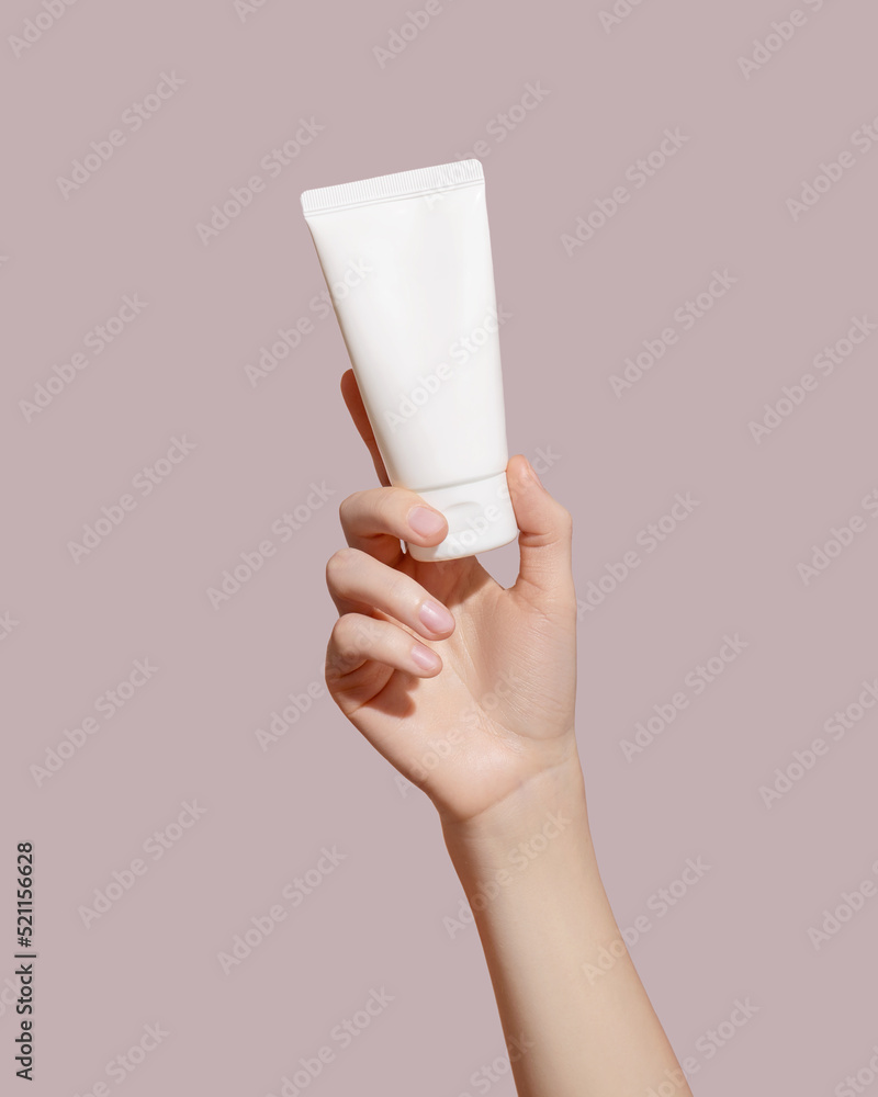 Hand holding blank white plastic tube on pink background. Cosmetic ...