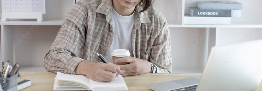 Young student does his homework and is broadcast live on his laptop ...