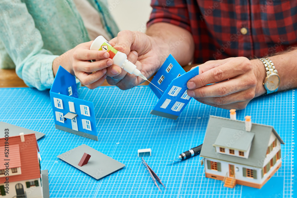 Hobby of building scale miniature model of house. Dad with child gluing ...
