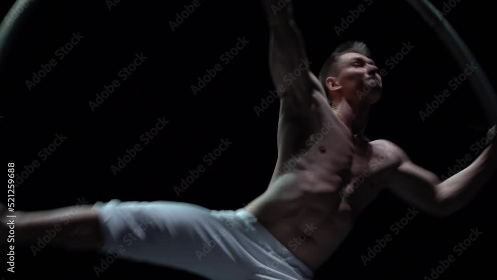 Muscular circus artist perform Cyr Wheel on a black background stage ...