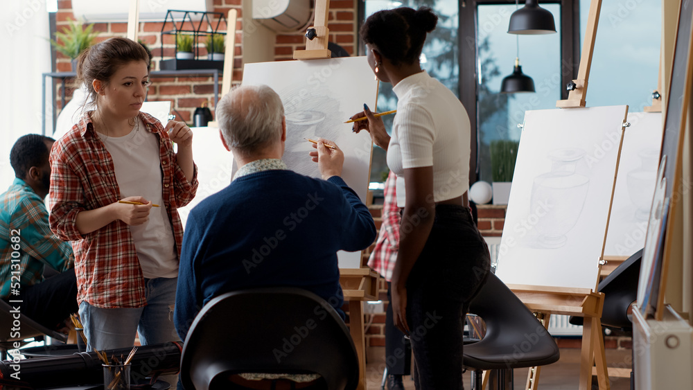 Diverse team of women giving drawing lesson to elder person attending ...