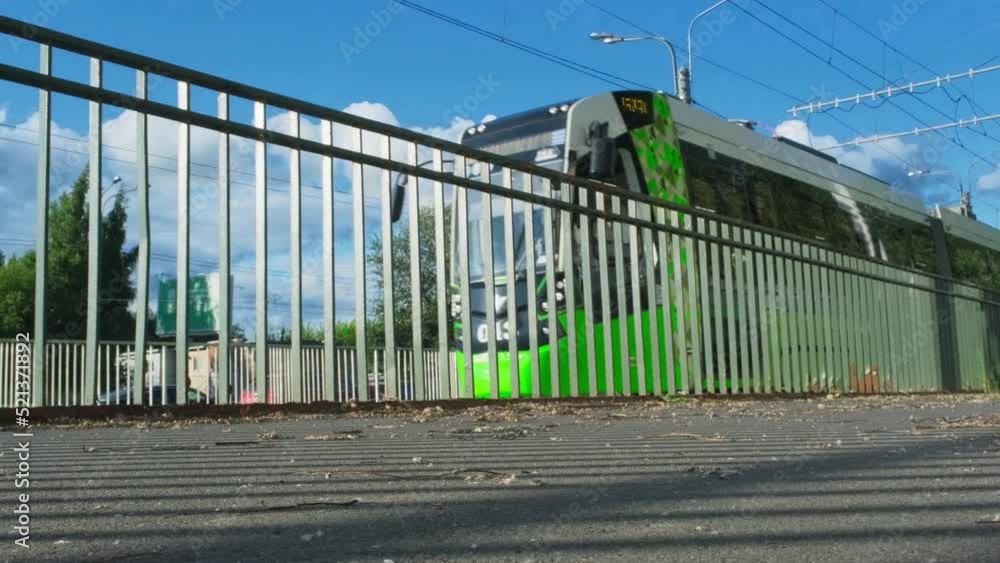 A tram passing behind a security fence. Railings protecting from the ...
