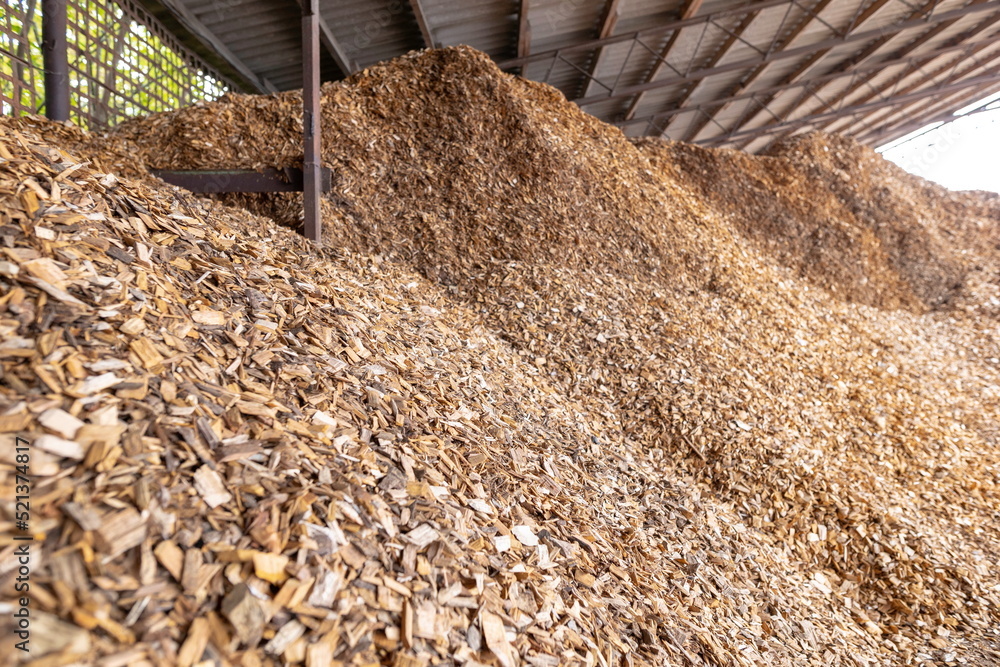 piles of hardwood wood chips are stored under the canopy as solid fuel ...