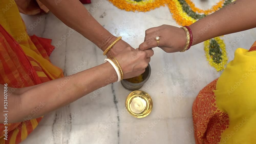 Close up shot of three women grinding turmeric for her wedding ceremony ...