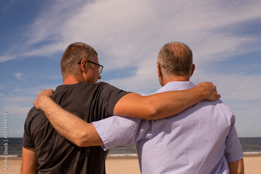 The two men put their hands on each other's shoulders and look at the seashore. Stock Photo ...