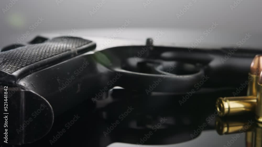Gun Control. 9mm handgun with bullets rotating on a reflective surface ...