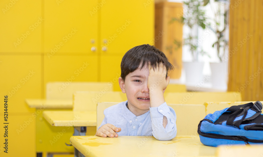 preschooler boy is crying sitting on school desk. angry unhappy sad ...