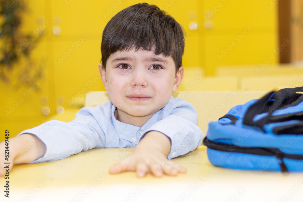 preschooler boy is crying sitting on school desk. angry unhappy sad ...