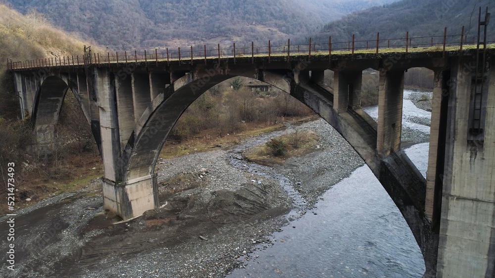 Aerial of an old abandoned mossy bridge over the almost dried out river ...