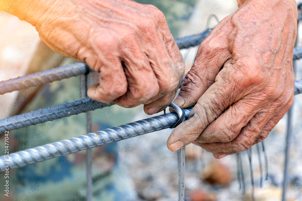 Workers are using steel wire to bind steel bars for foundation ...
