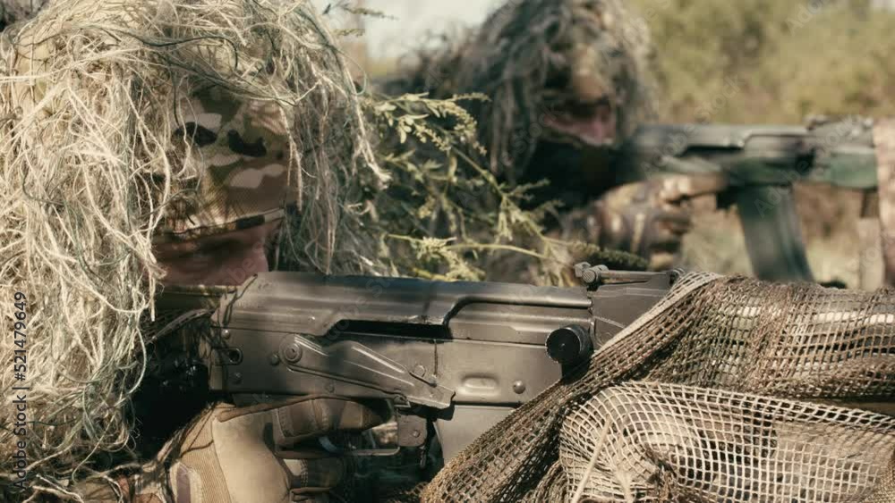 A close-up of a sniper wearing a camouflage suit or grass cloak ...