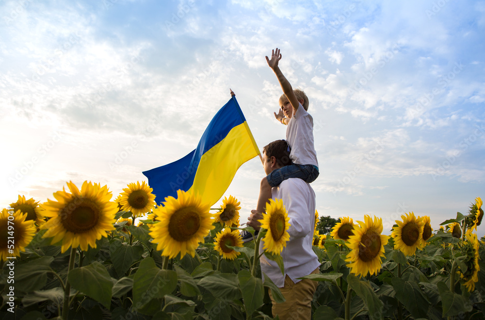 dad with son, who sits on his shoulders, with large flag of Ukraine ...