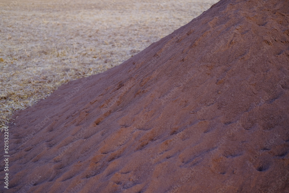 large pile of brown loose fertilizer on sloping field, agrochemistry ...